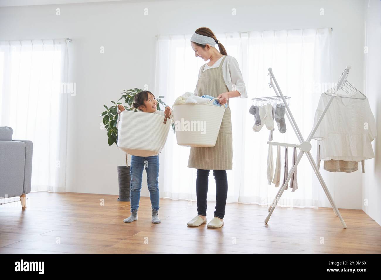 Parent and child drying laundry in living room Stock Photo - Alamy