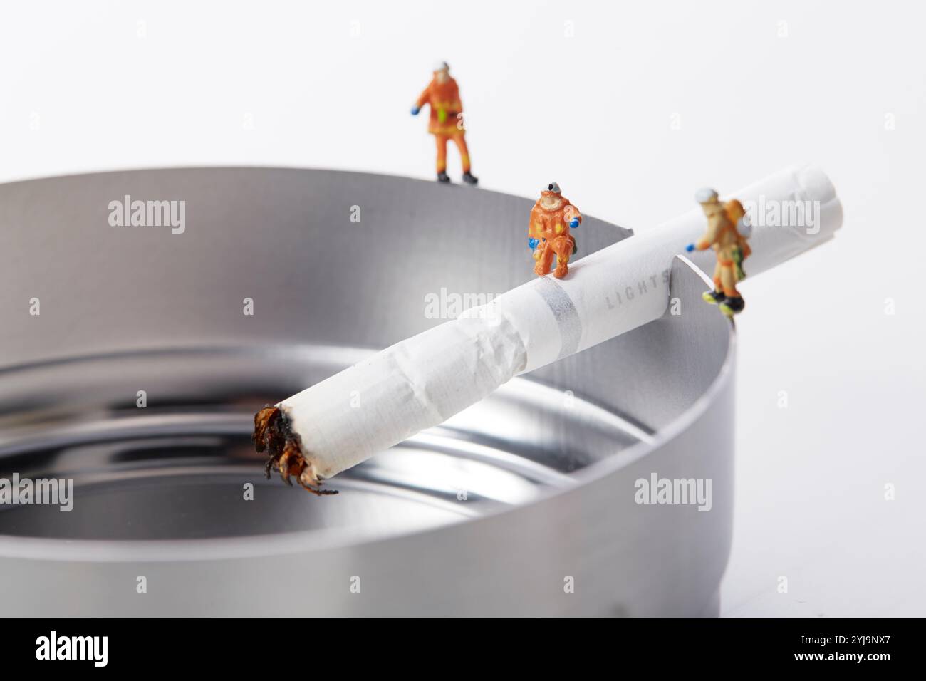 Cigarette butts and miniature firefighters Stock Photo - Alamy