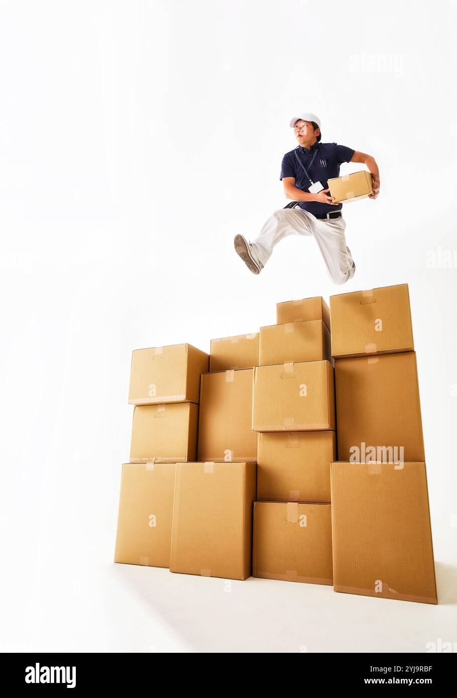 Man in work clothes jumping over many piles of cardboard boxes Stock Photo - Alamy