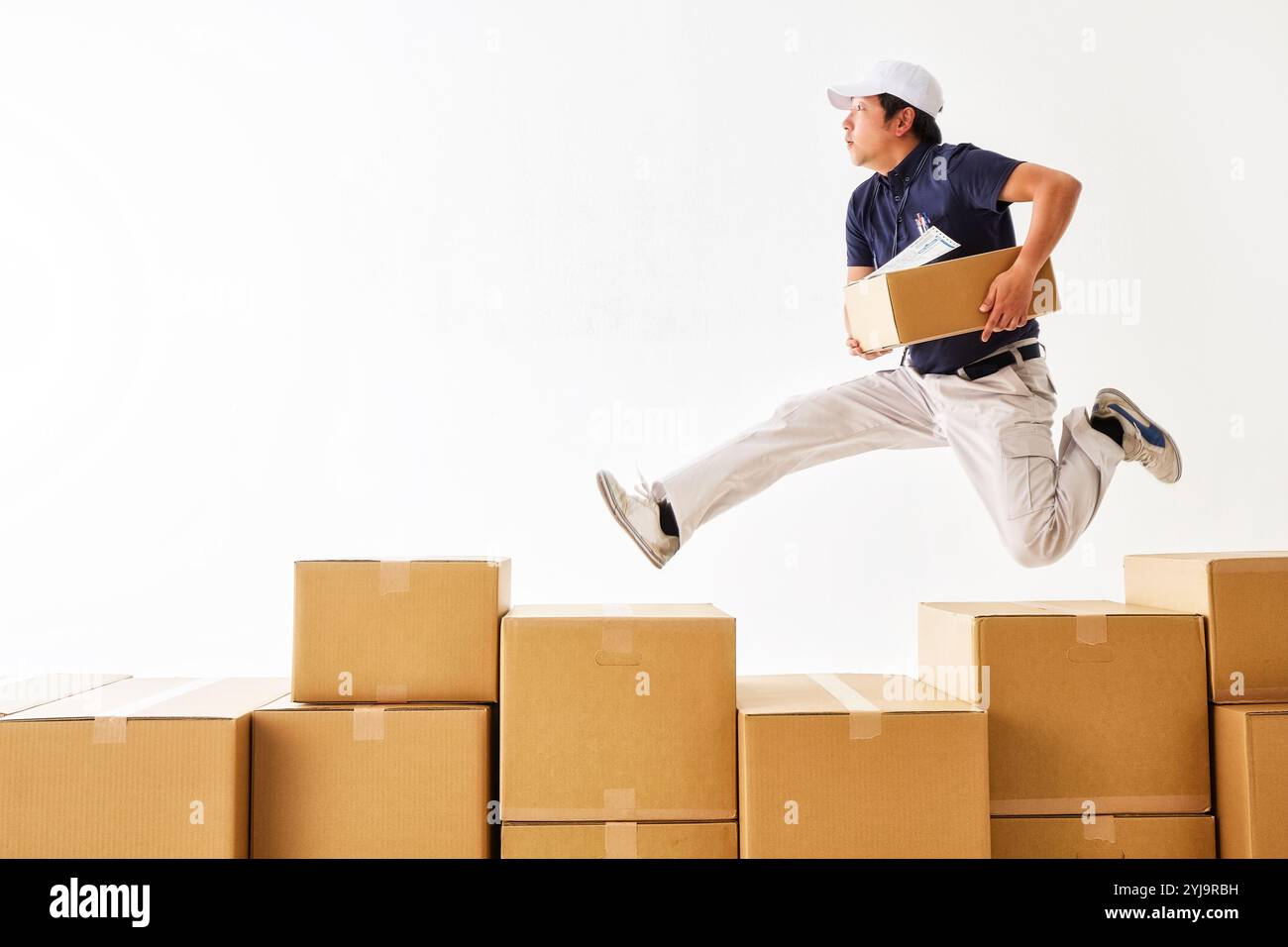 Man in work clothes jumping behind lined cardboard boxes Stock Photo - Alamy