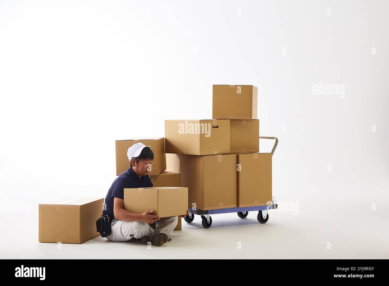 Man in work clothes sitting down after dropping a cart load in a white ...