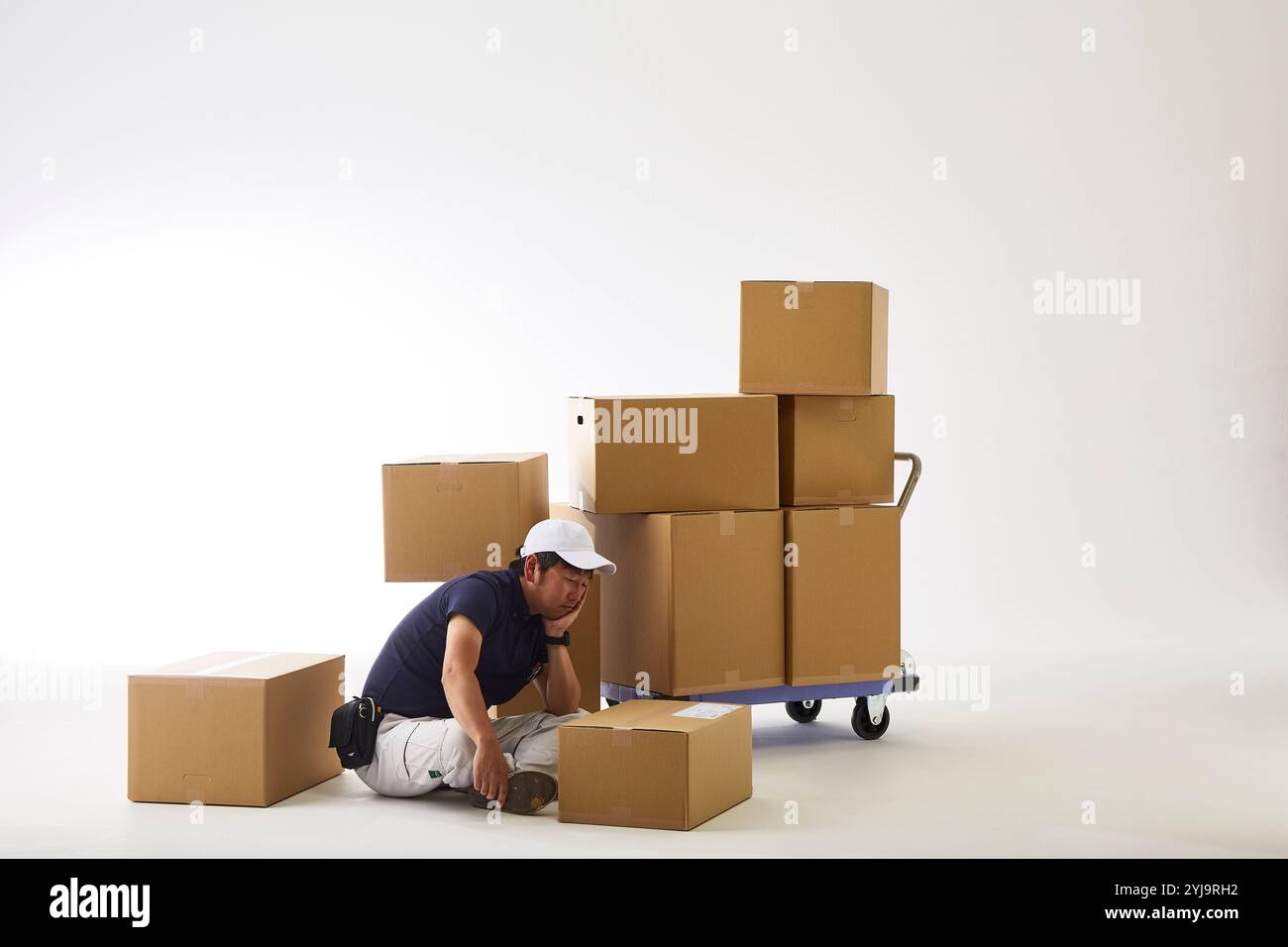 Man in work clothes sitting down after dropping a cart load in a white ...