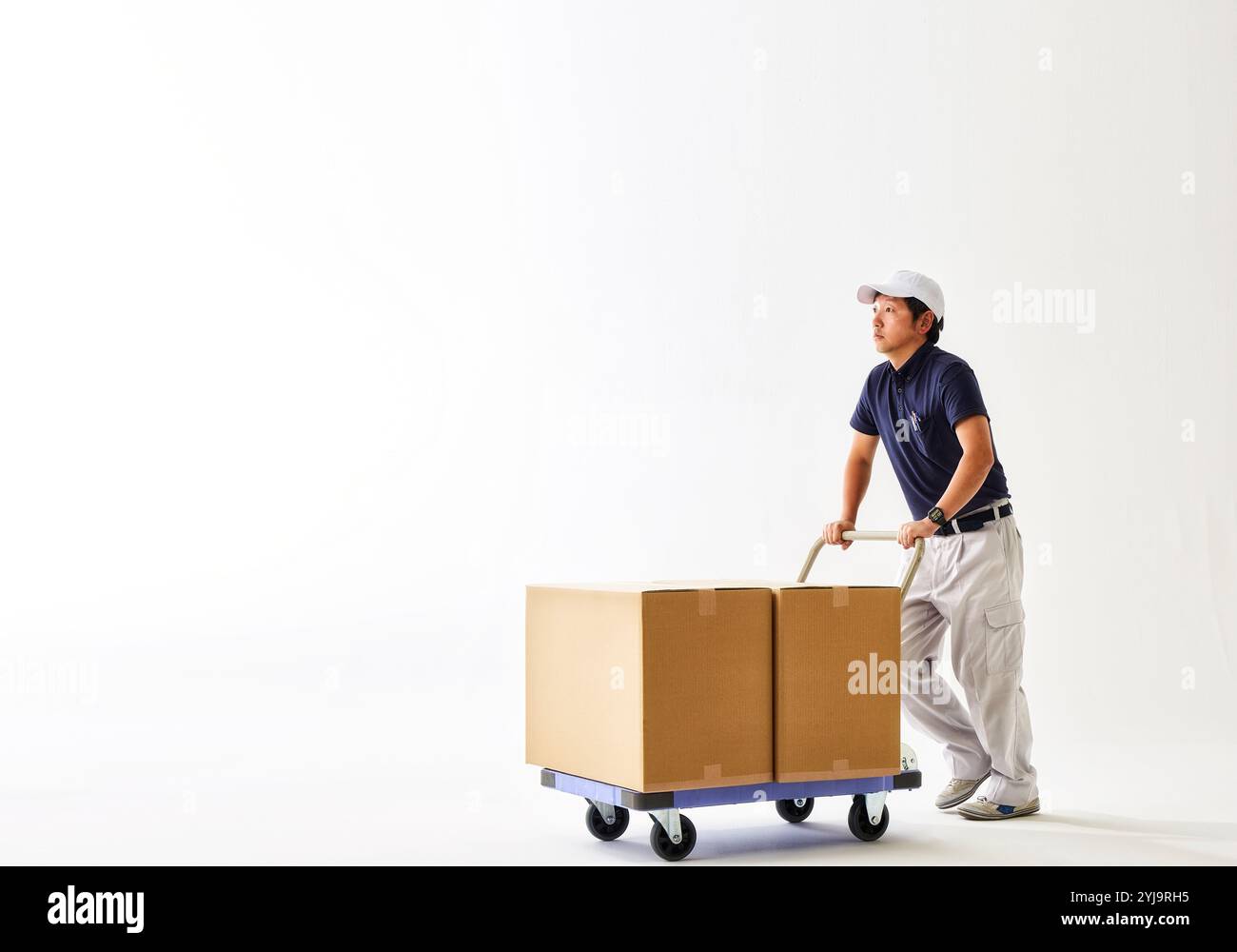 Man in work clothes carrying a trolley with luggage in a white-backed ...