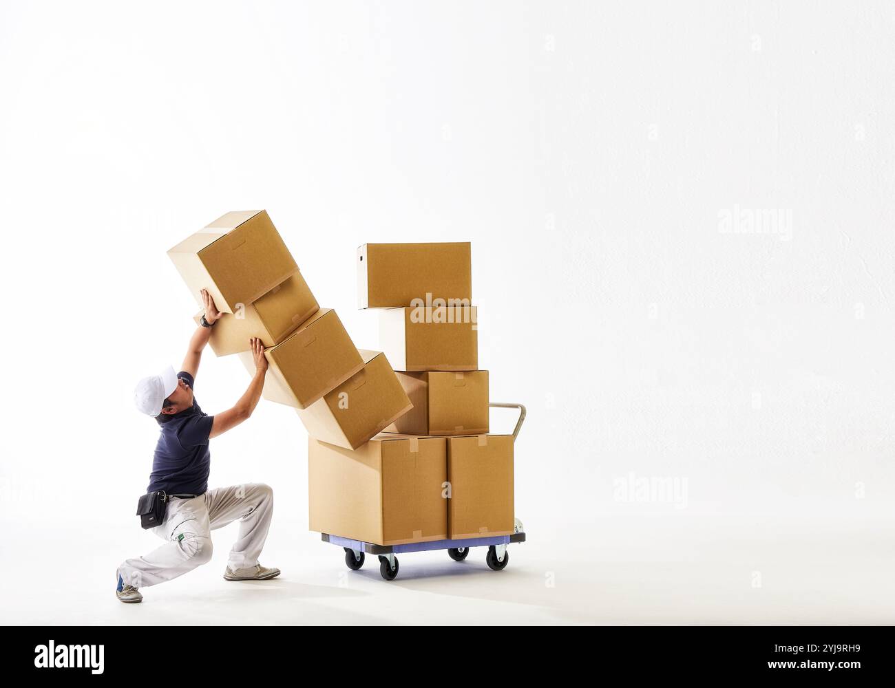 Man in work clothes holding down a cart load in the space of the white ...