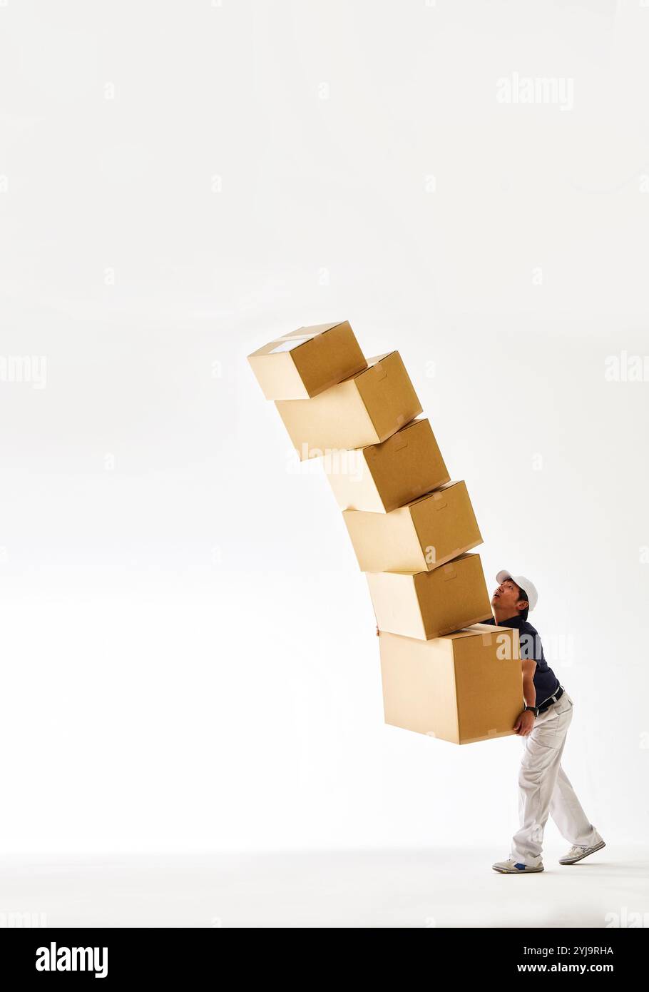 Man in work clothes carrying many stacks of cardboard boxes in white ...