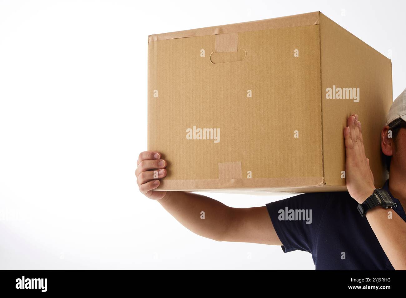 Man in work clothes holding a load on his shoulder standing in a white ...