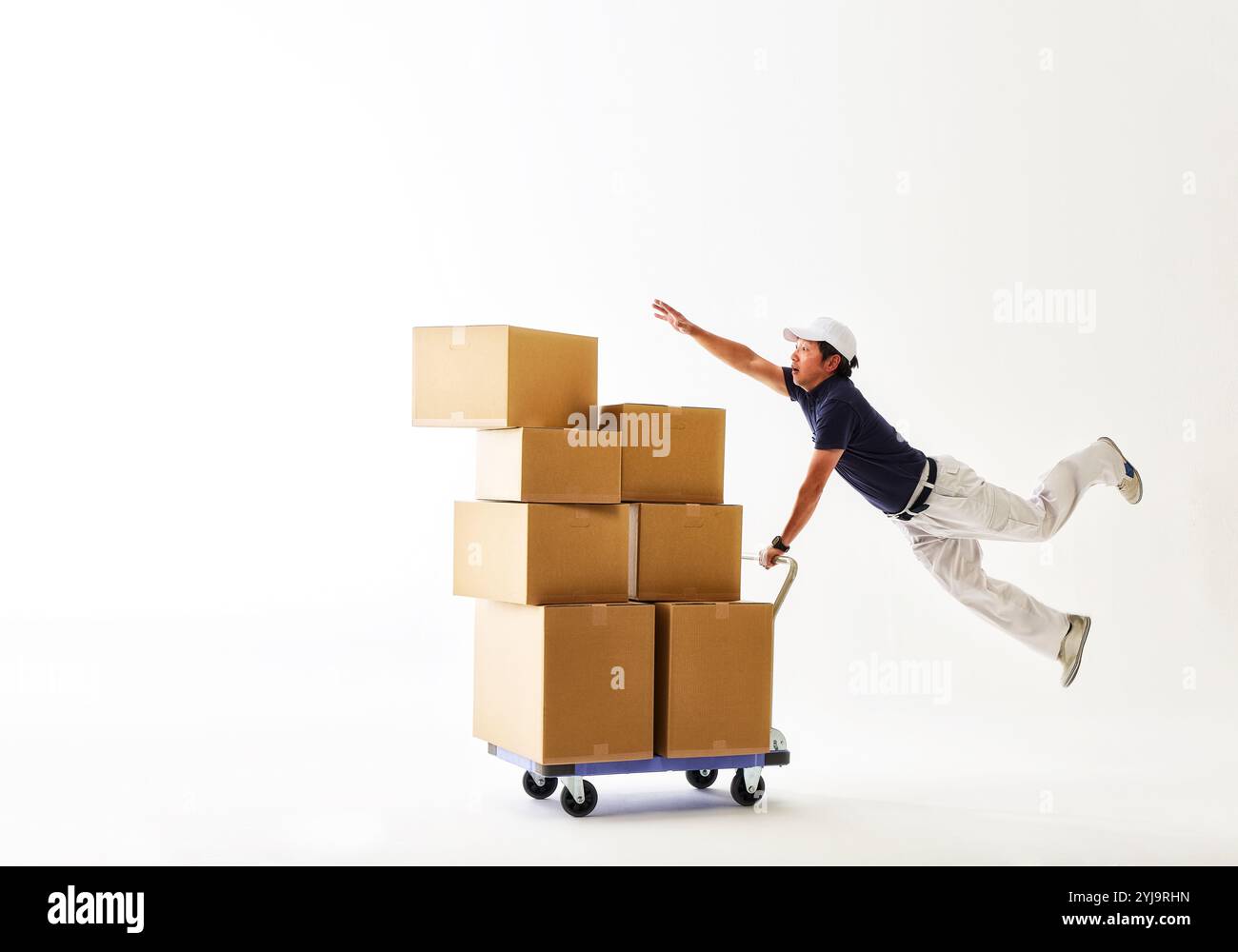 Man in work clothes flying almost dropping a cart load in a white ...