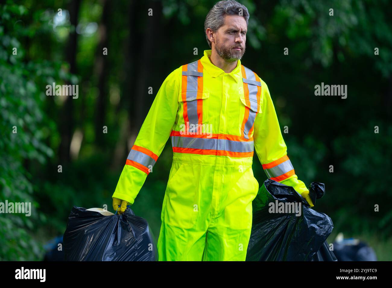 Man cleaning up the park, putting trash in a garbage bag. Environmental ...