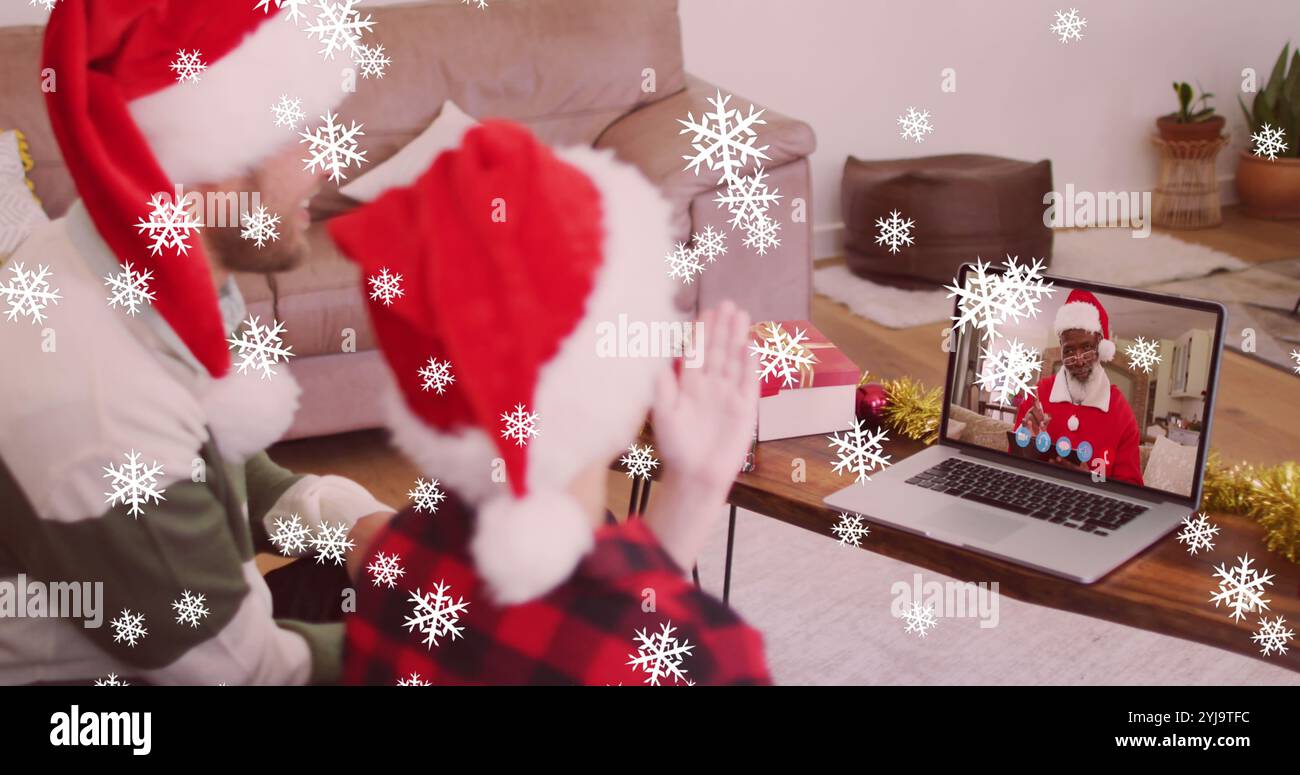 Image of snow falling over smiling father and son in santa hats on ...