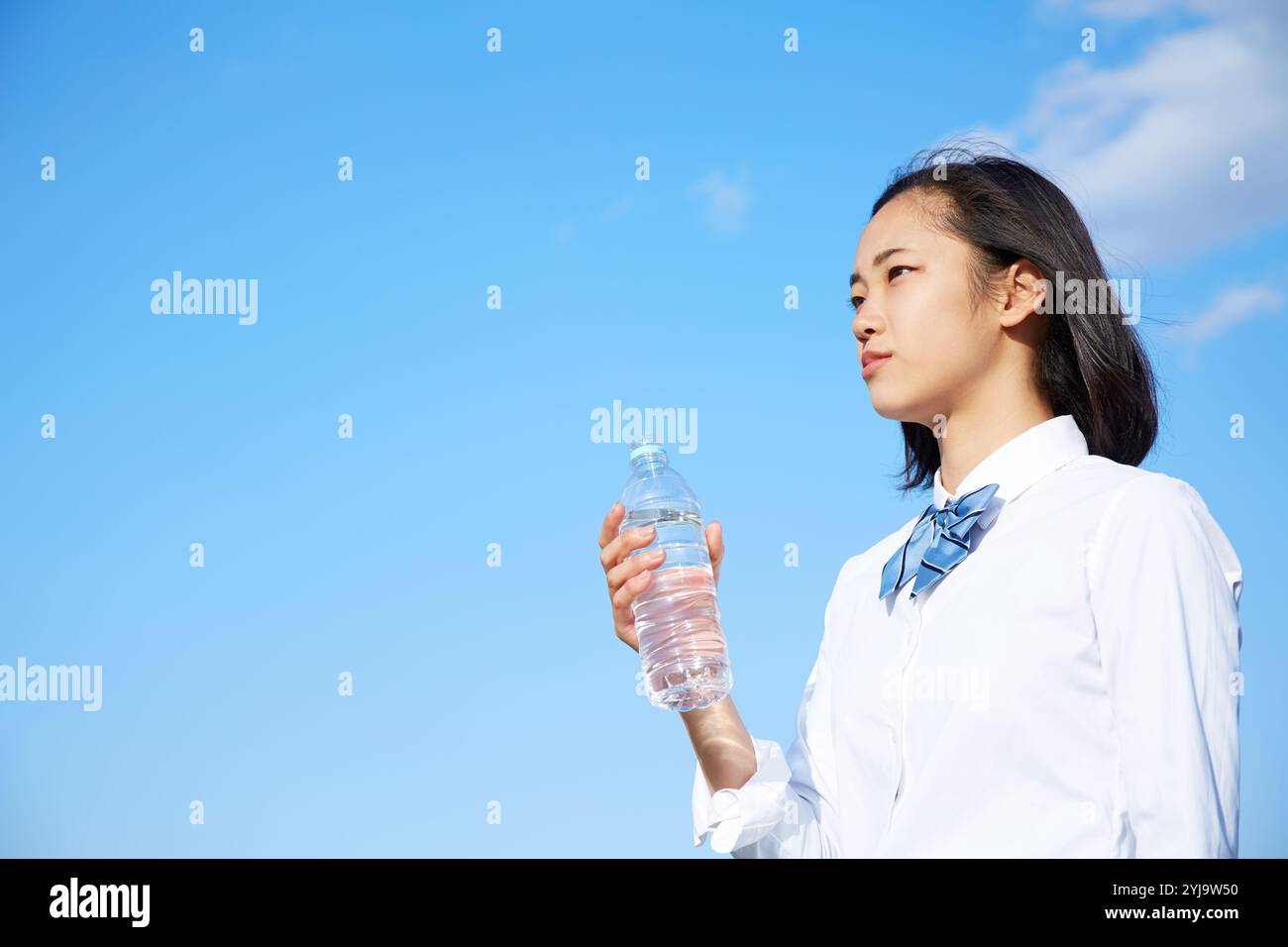 High school girls drinking bottled water under a blue sky Stock Photo - Alamy