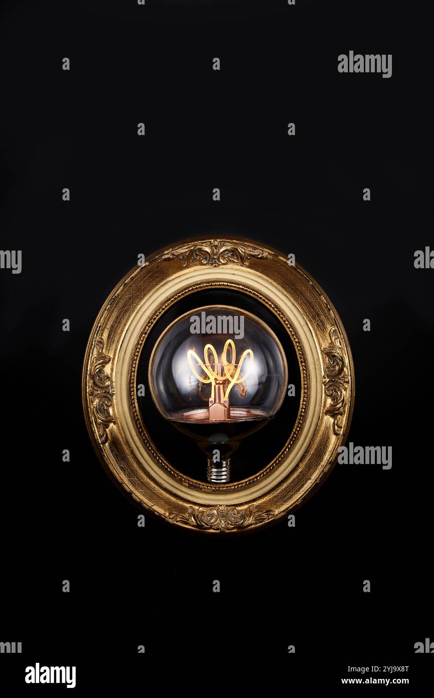 Oval frame and light bulb above black background Stock Photo - Alamy