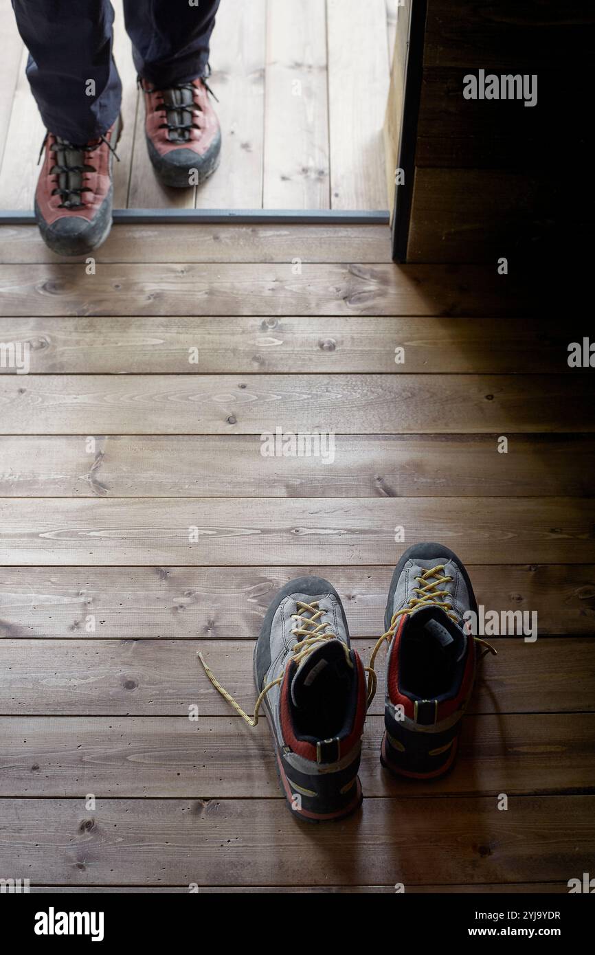 Trekking shoes on the floor near the hut entrance and people entering ...
