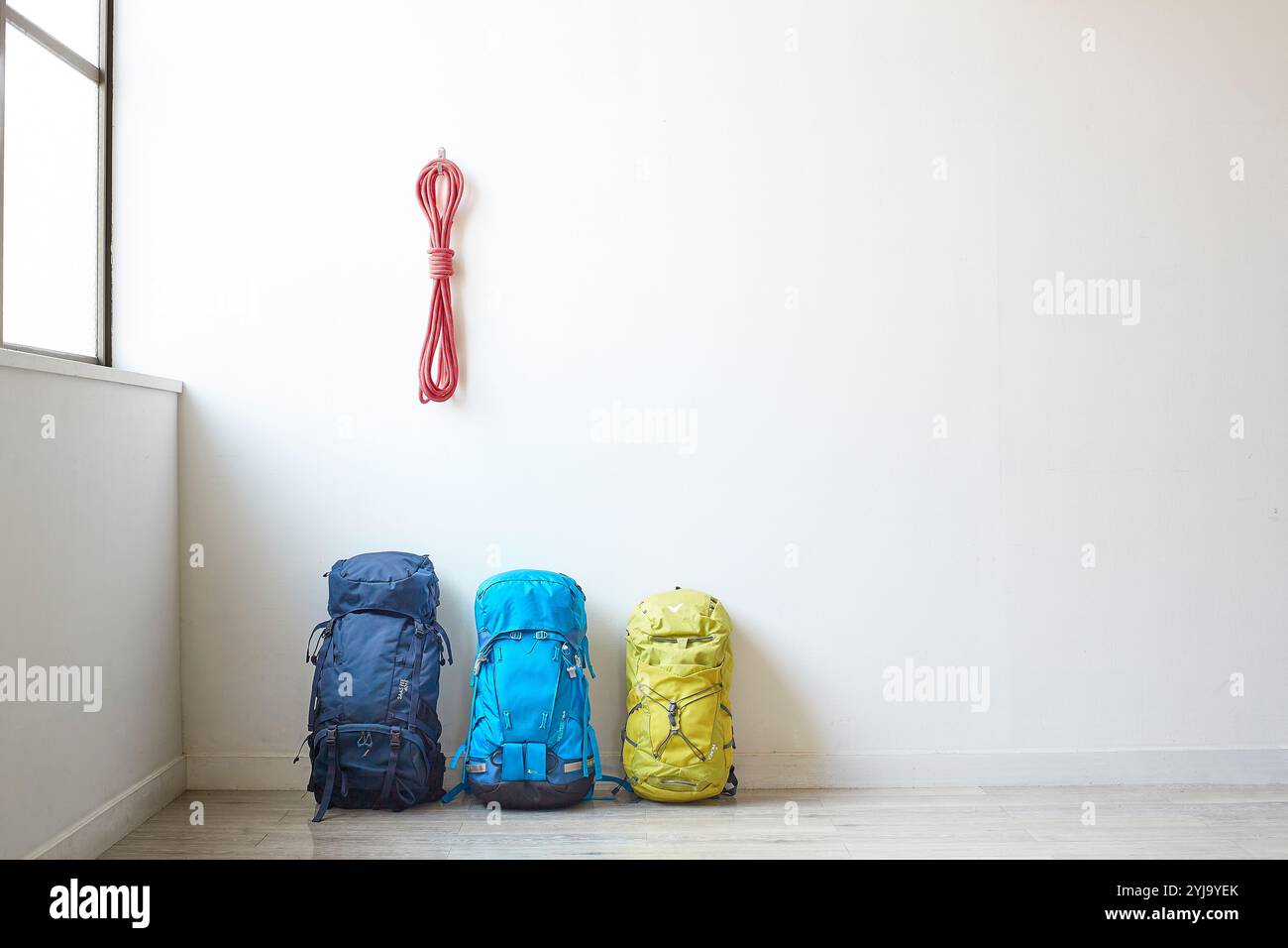 Climbing rope hanging on the white wall by the window and three ...