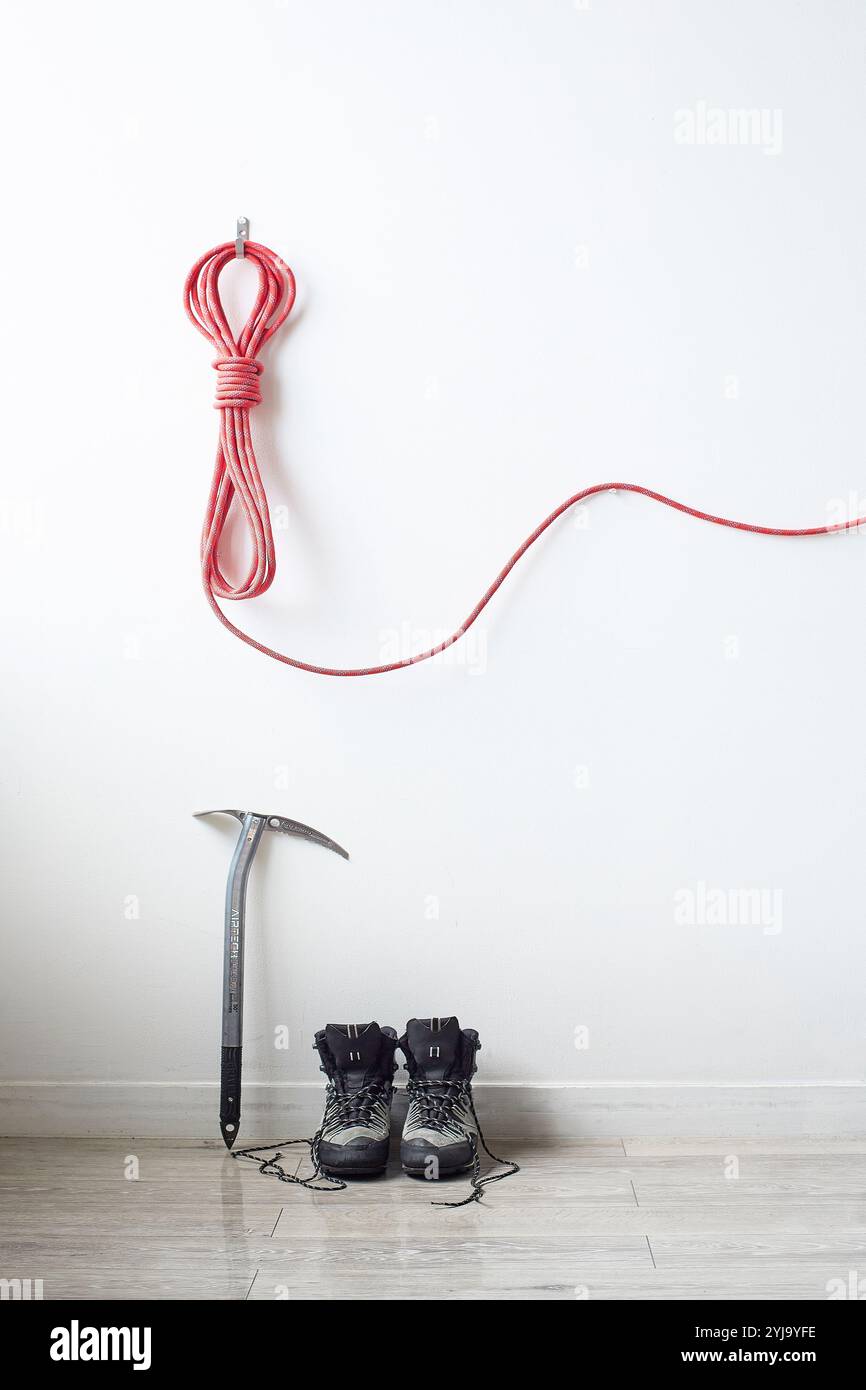 A mountaineering rope stretched out over a white wall, a pair of ice ...