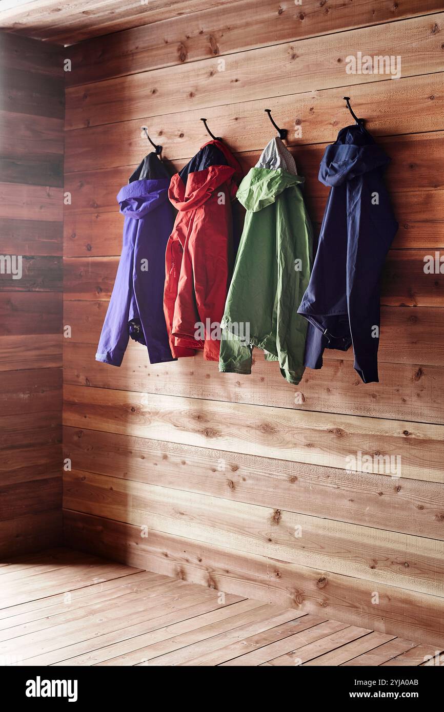 Four colours of mountaineering clothing hanging on hooks inside the hut ...