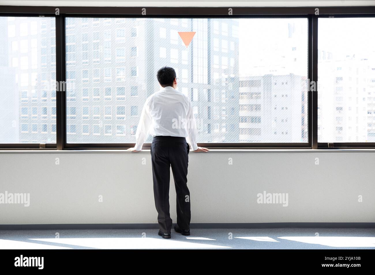 Back view of businessman standing in front of window looking out Stock ...