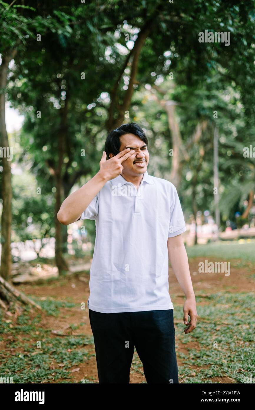 Southeast Asian man rubbing his eyes, expressing fatigue or discomfort ...
