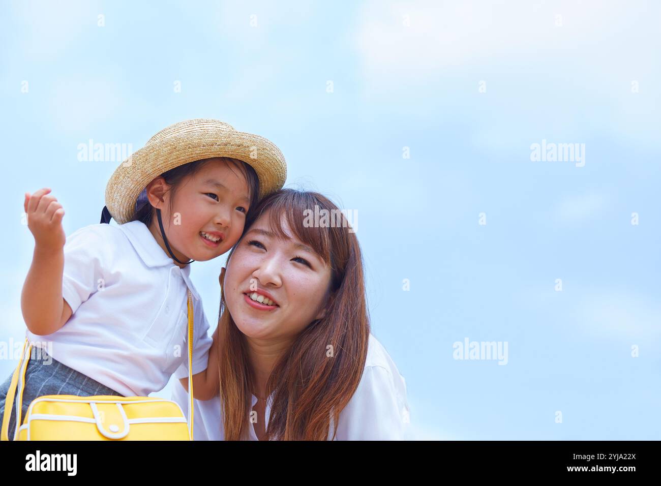 Mother and child sliding cheek to cheek and laughing against the blue ...