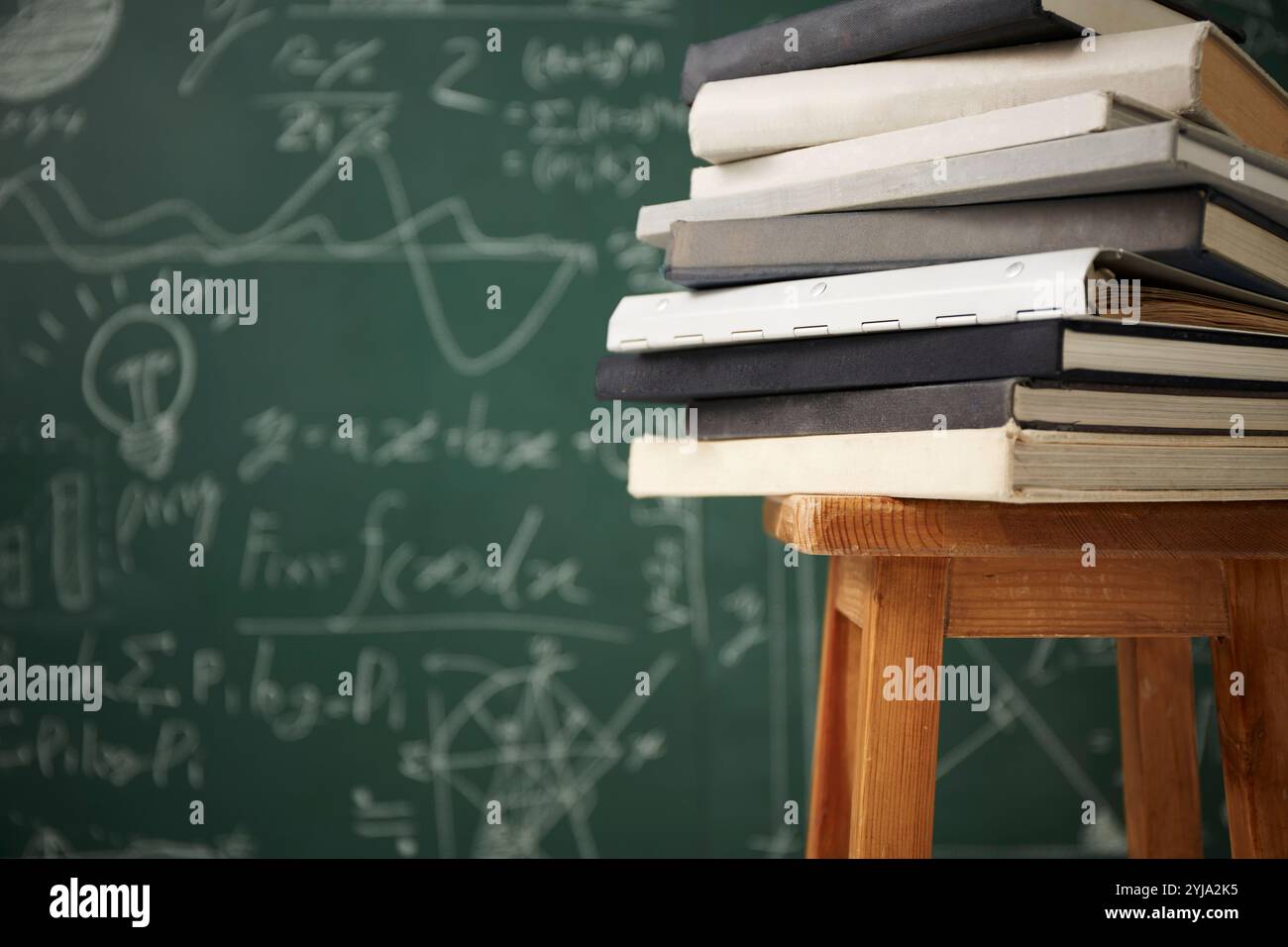 Books stacked on chairs in front of the blackboard Stock Photo - Alamy