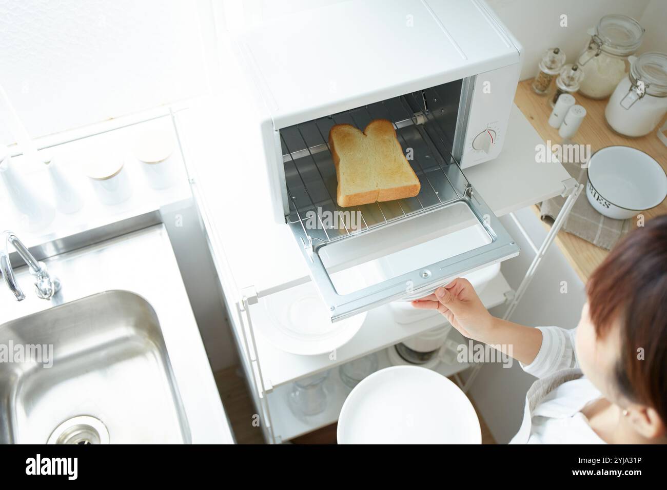 Woman baking bread in toaster Stock Photo - Alamy