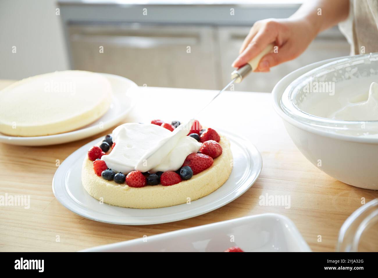 Woman's hand putting cream on cake Stock Photo - Alamy