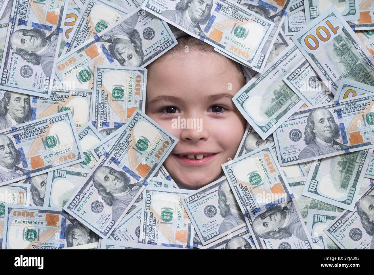 Kid with fun face in money. Kid peeking out of dollar bills with ...