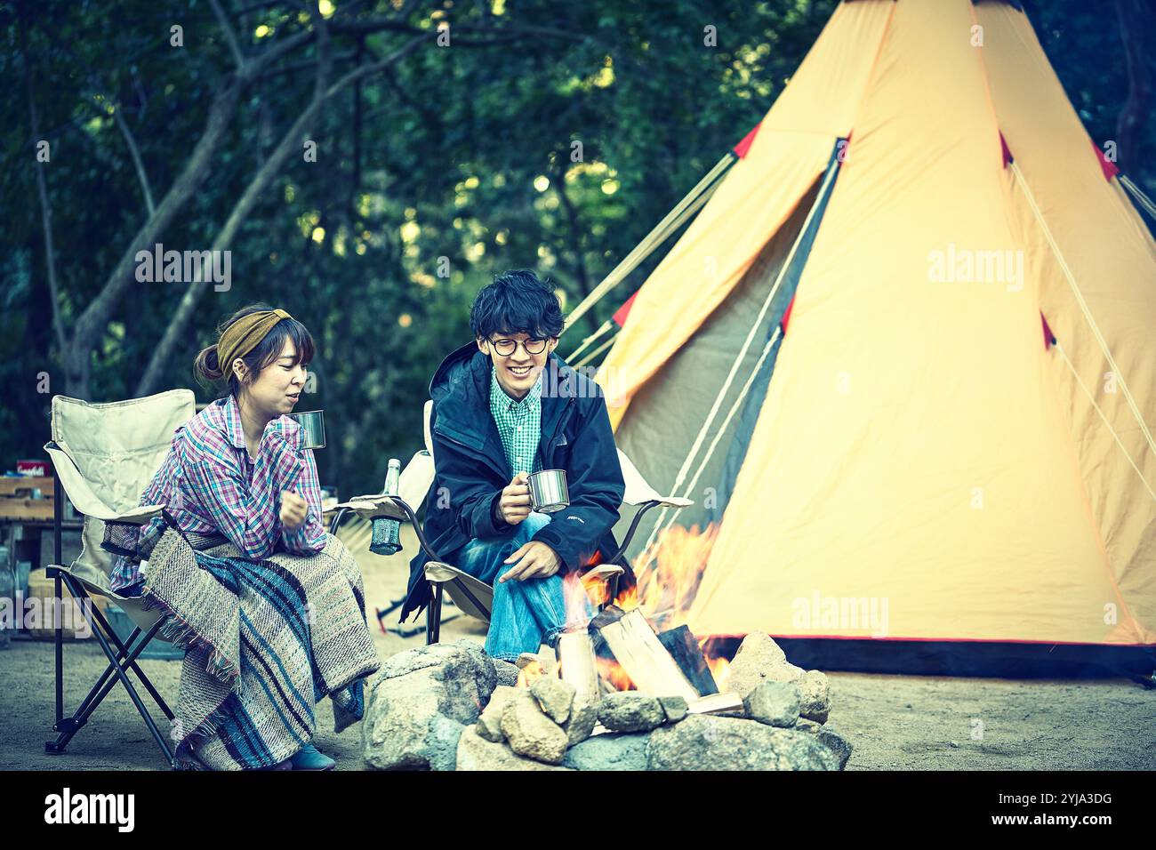 Two people making a bonfire in front of a tent Stock Photo - Alamy