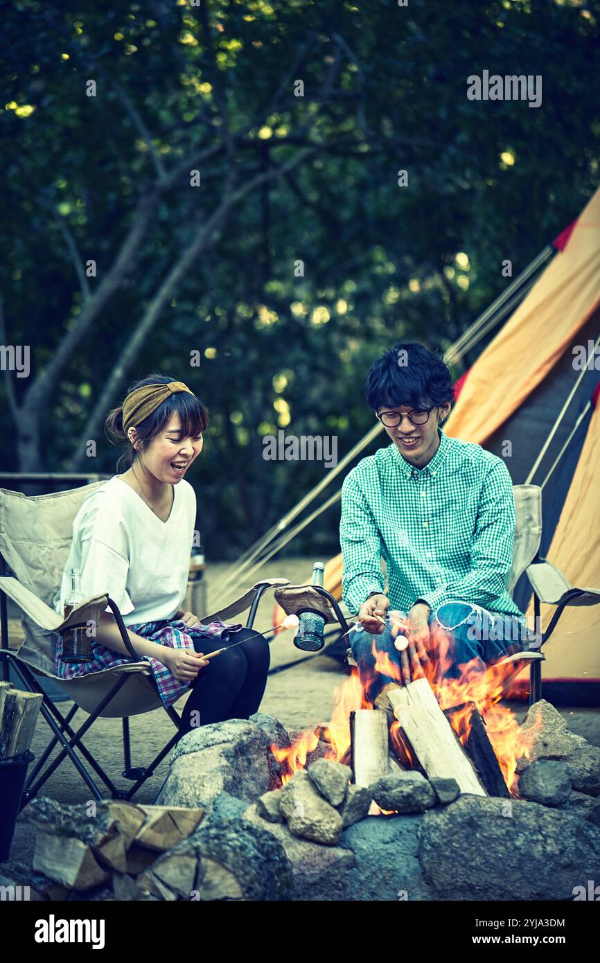 Two people making a bonfire in front of a tent Stock Photo - Alamy