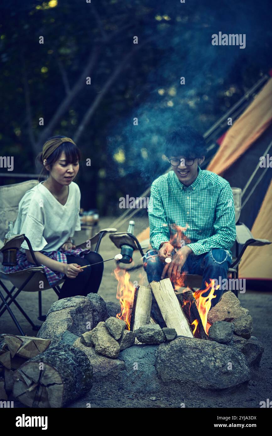 Two people making a bonfire in front of a tent Stock Photo - Alamy