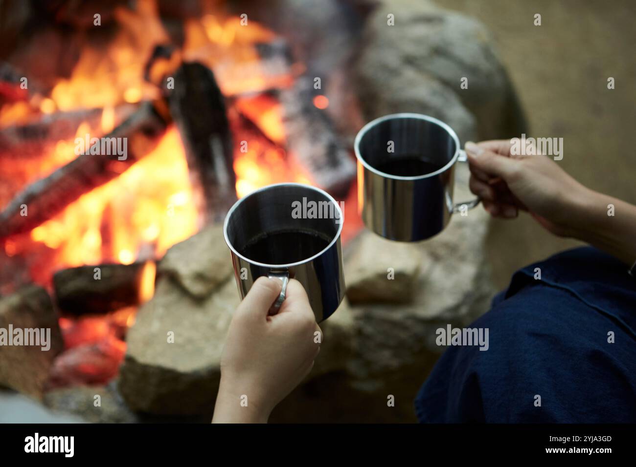 Two people drinking coffee around a bonfire Stock Photo - Alamy