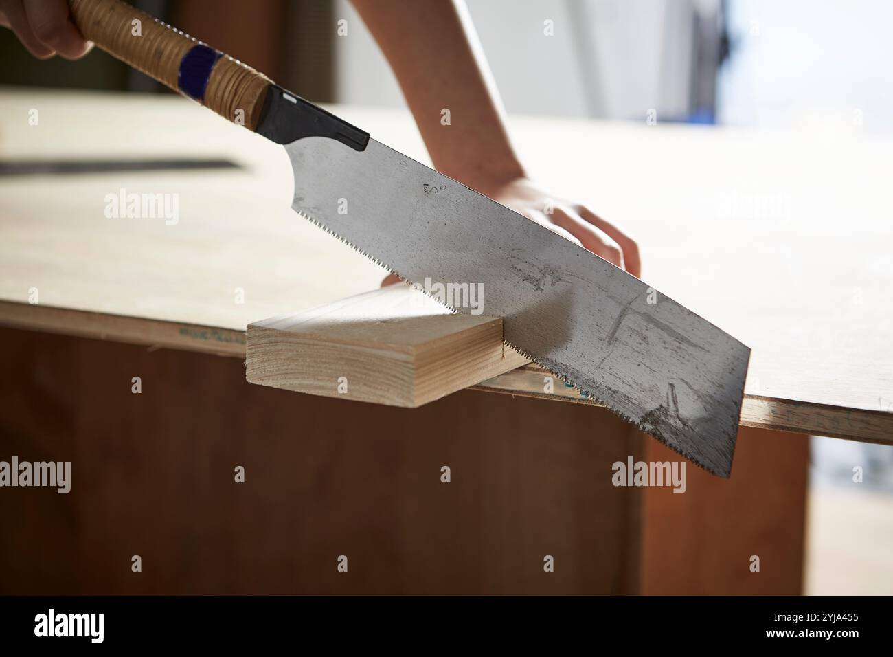 Man cutting wood with saw Stock Photo - Alamy