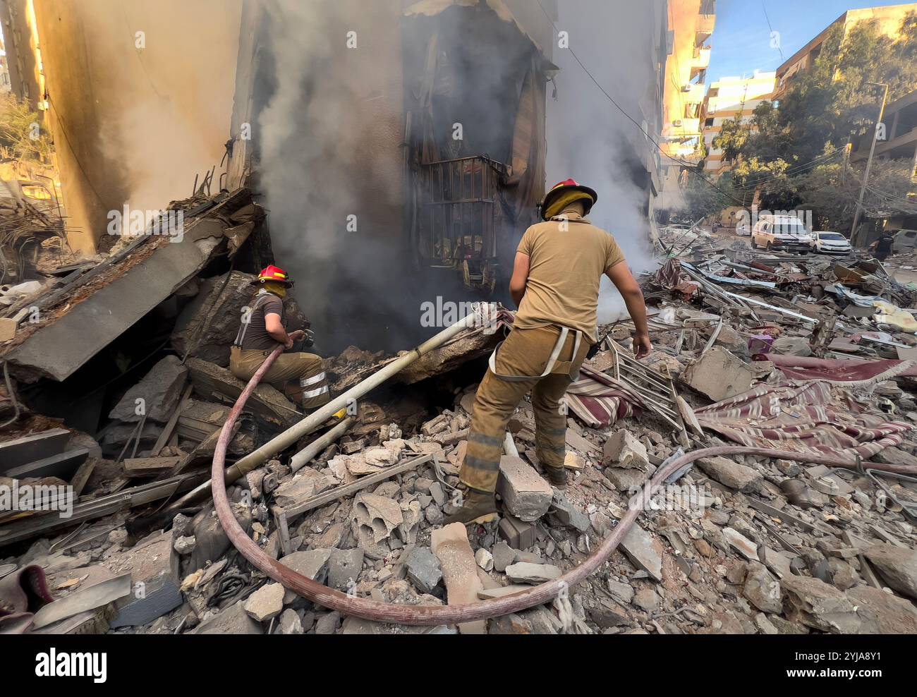 Firefighters extinguish a fire as smoke rises from a building destroyed ...