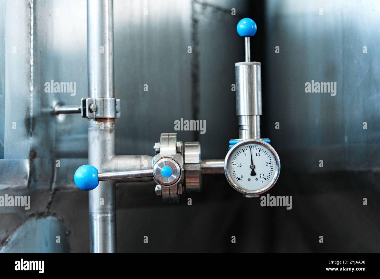 A close-up of a pressure gauge and valve attached to a pipe in a ...