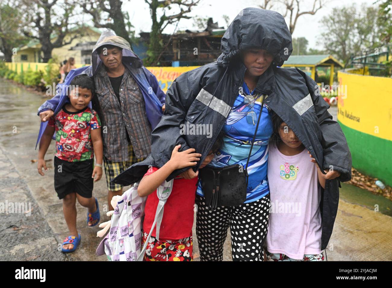 Residents use jackets to protect them from rain as they evacuate their ...
