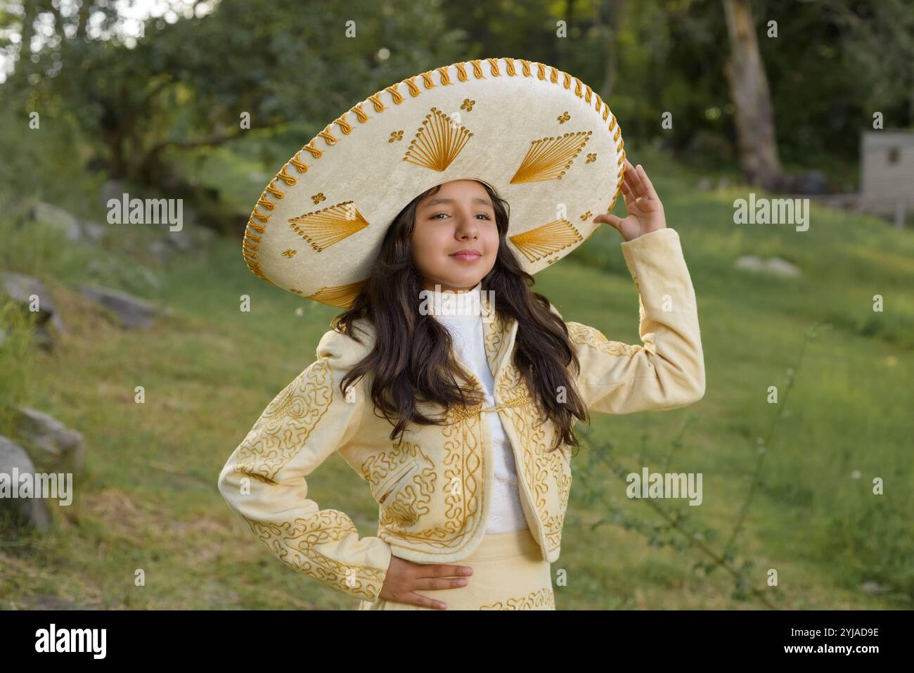Girl wearing a charro dress with mariachi hat in rural scenery. Mexican ...