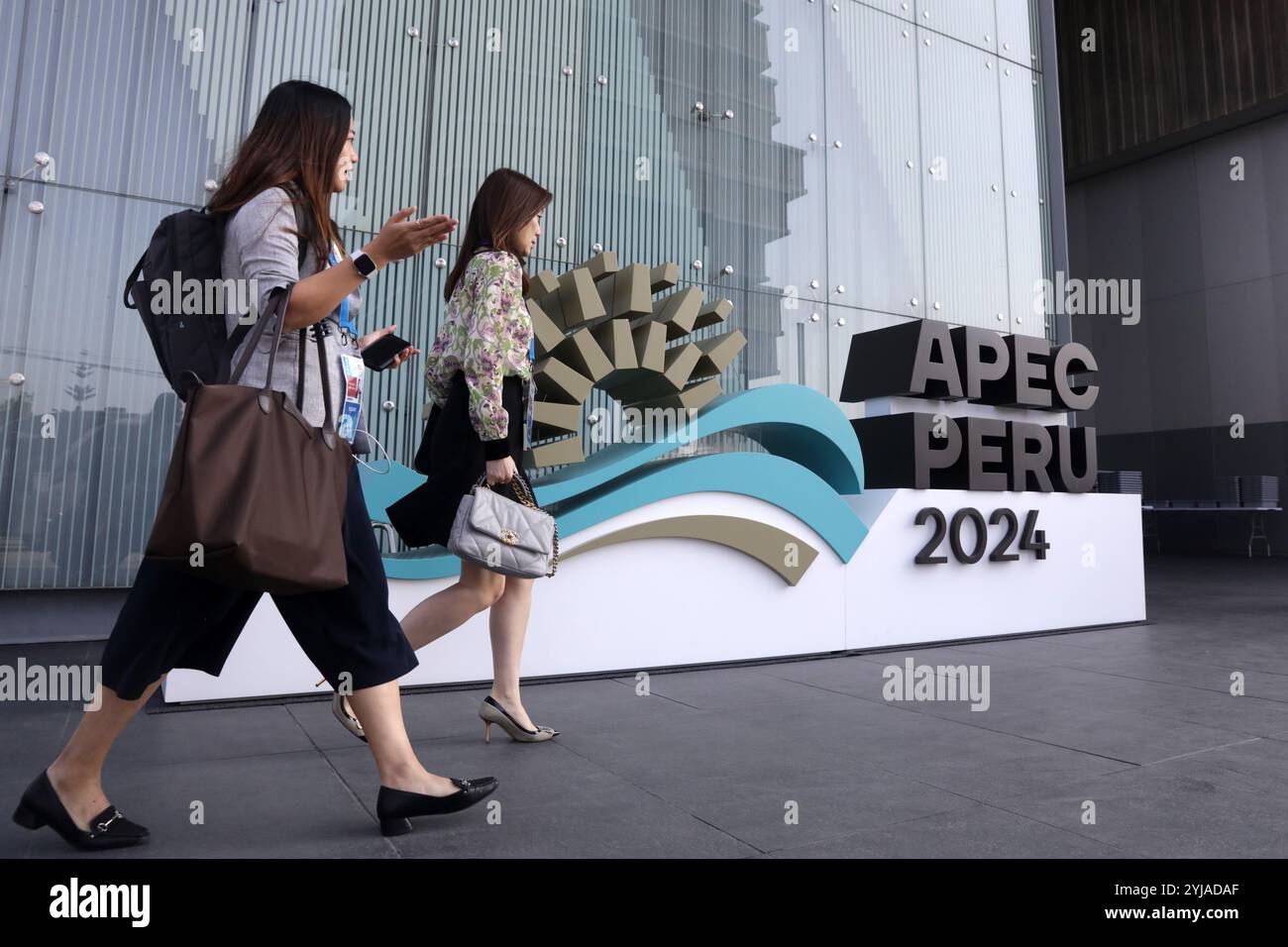 Lima, Peru. 13th Nov, 2024. People walk past the logo of APEC 2024 outside the Lima Convention ...