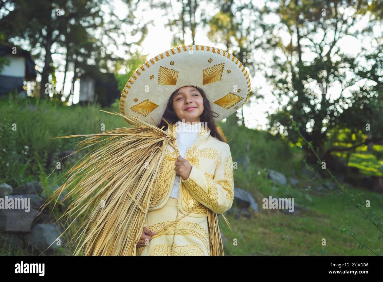 Girl wearing a charro dress with mariachi hat in rural scenery. Mexican ...