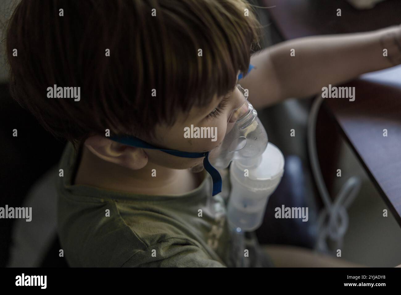 A young child using a nebulizer mask for asthma and respiratory ...