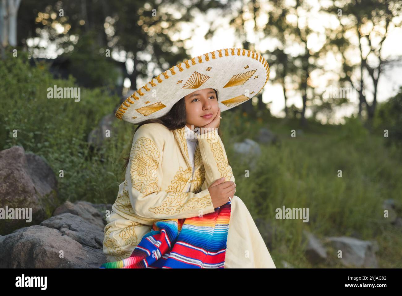Girl wearing a charro dress with mariachi hat in rural scenery. Mexican ...