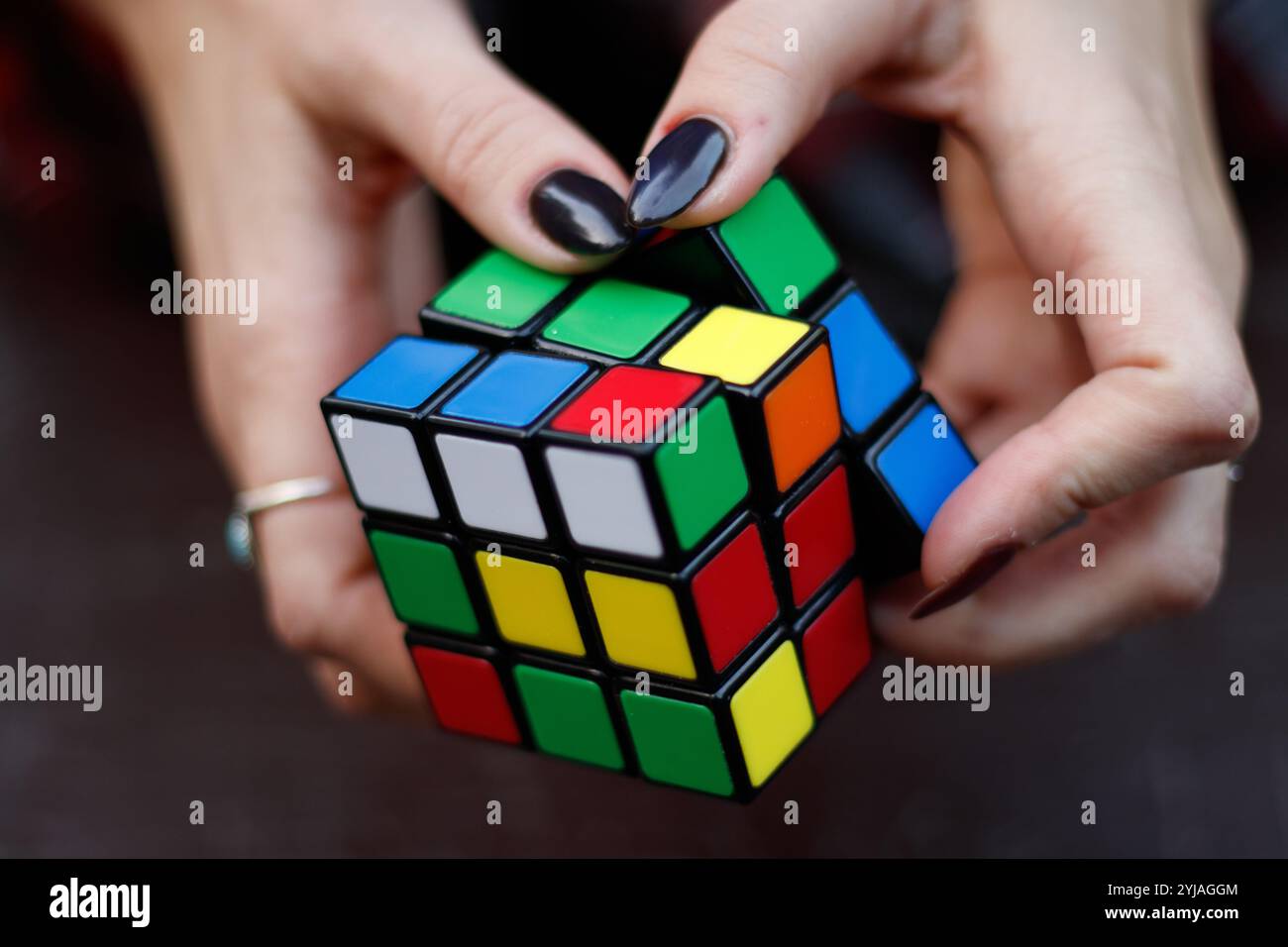 Vancouver, Canada - Oct1,2019: Hands manipulating a colorful Rubik's cube puzzle against dark ...