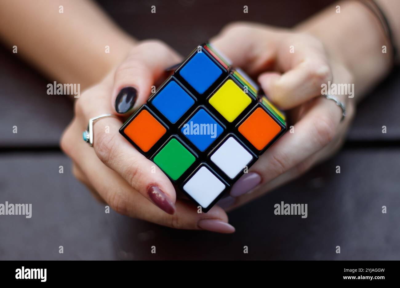 Vancouver, Canada - Oct1,2019: Hands manipulating a colorful Rubik's cube puzzle against dark ...