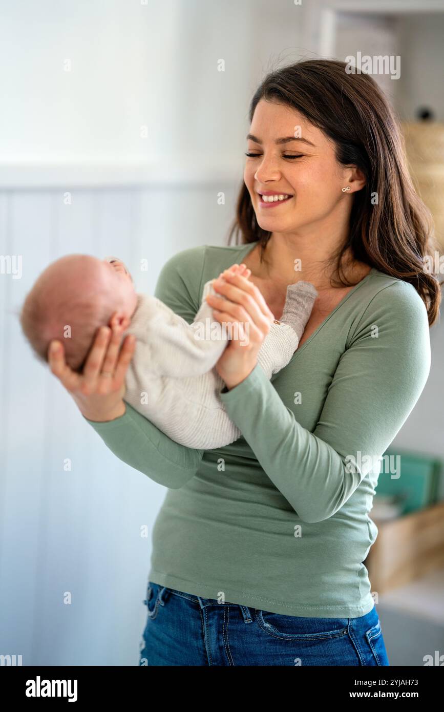 Loving single mother carrying of her newborn baby at home. People love ...