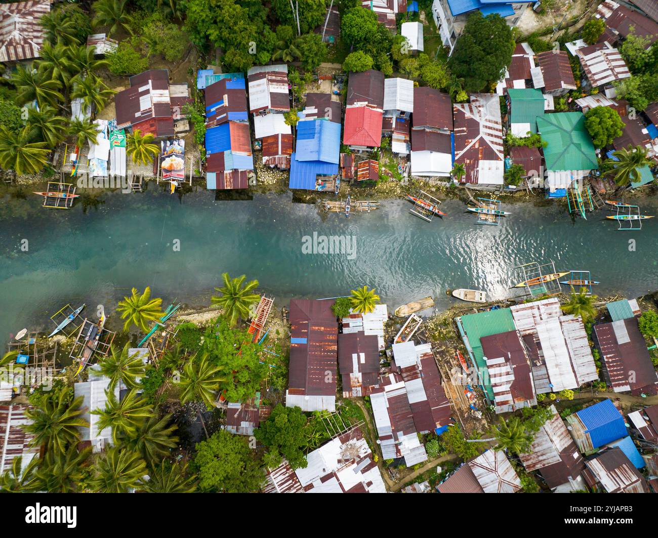Top view of fishermans villages and transparent turquoise cold spring river with boats. Surigao ...
