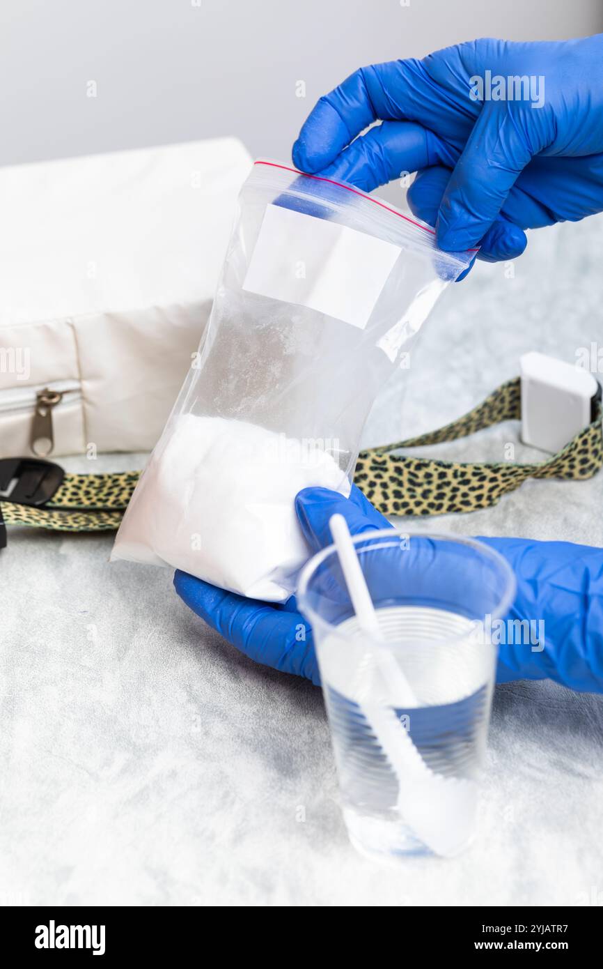 Gloved hands handling glucose monohydrate powder in a sealed bag for a ...