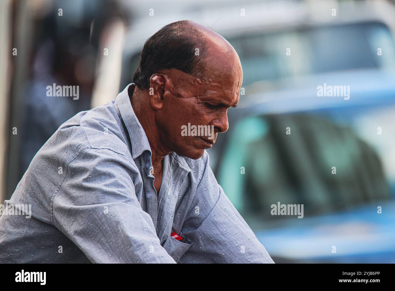 A local man is sitting on a bench in Mauritius, with his hands resting ...