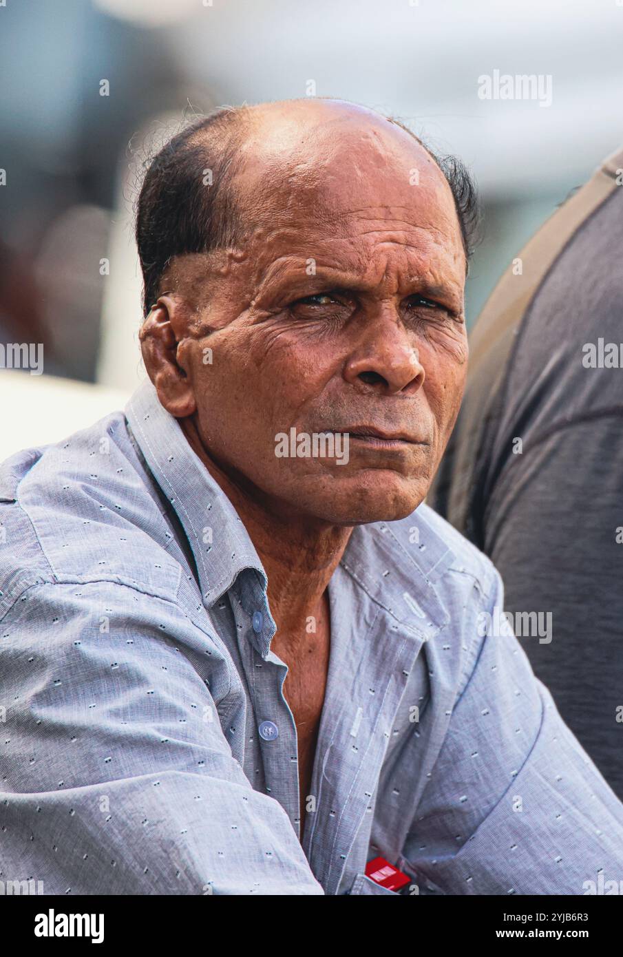 A local man in Mauritius sits on a bench, confidently placing his hand ...
