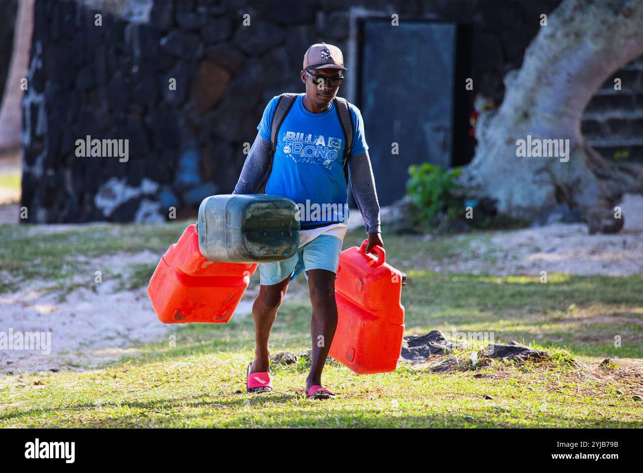 A portrait of a local man in Mauritius carrying three orange buckets on ...