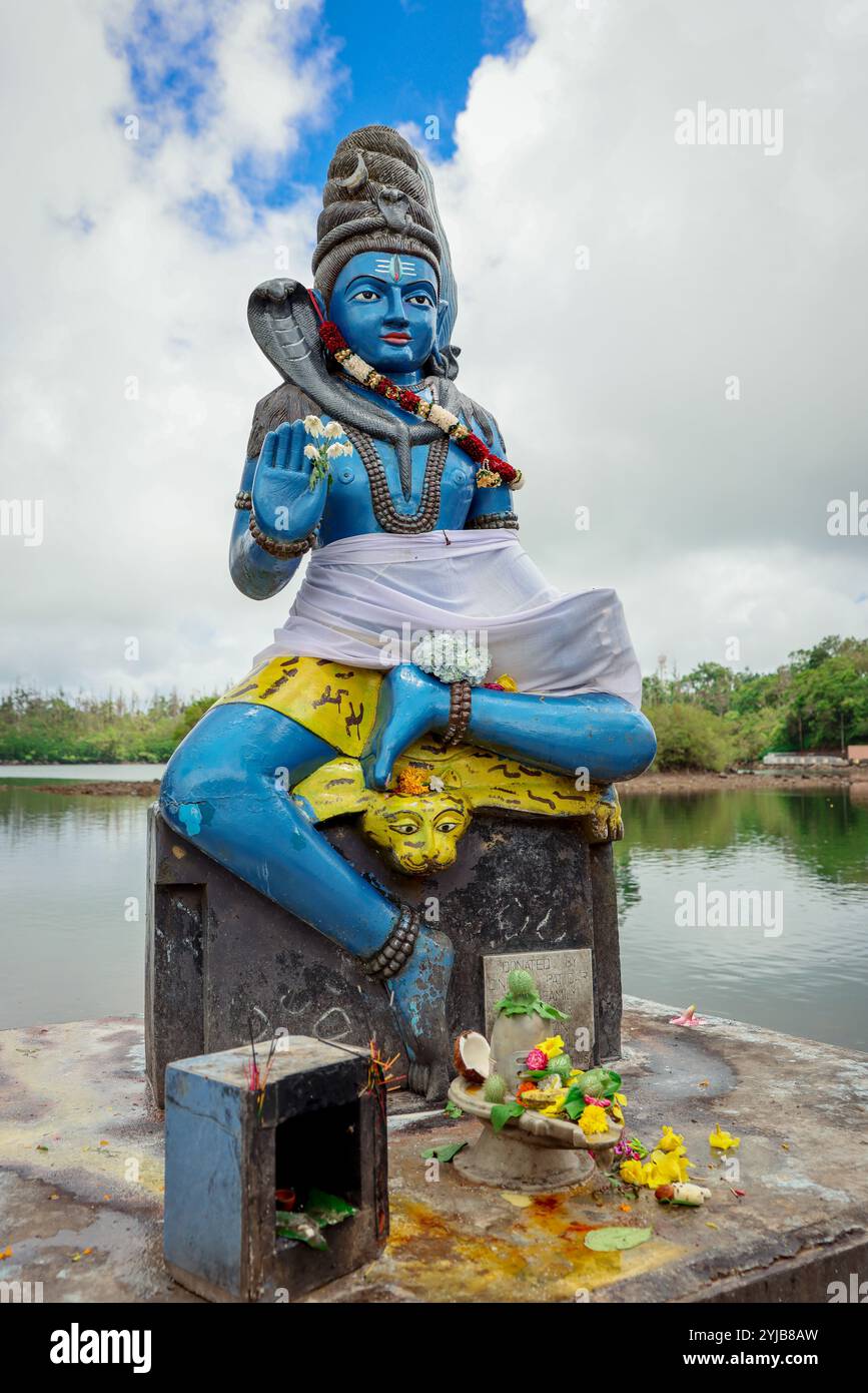 A statue of a Hindu person sitting on top of a cement block in ...