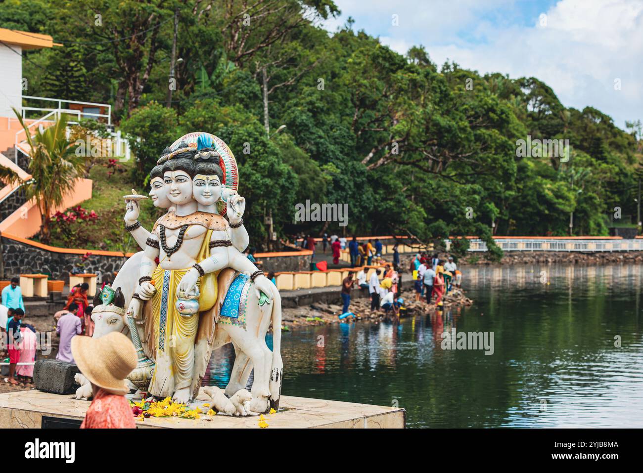 A statue of a Hindu deity on horseback stands next to a body of water ...