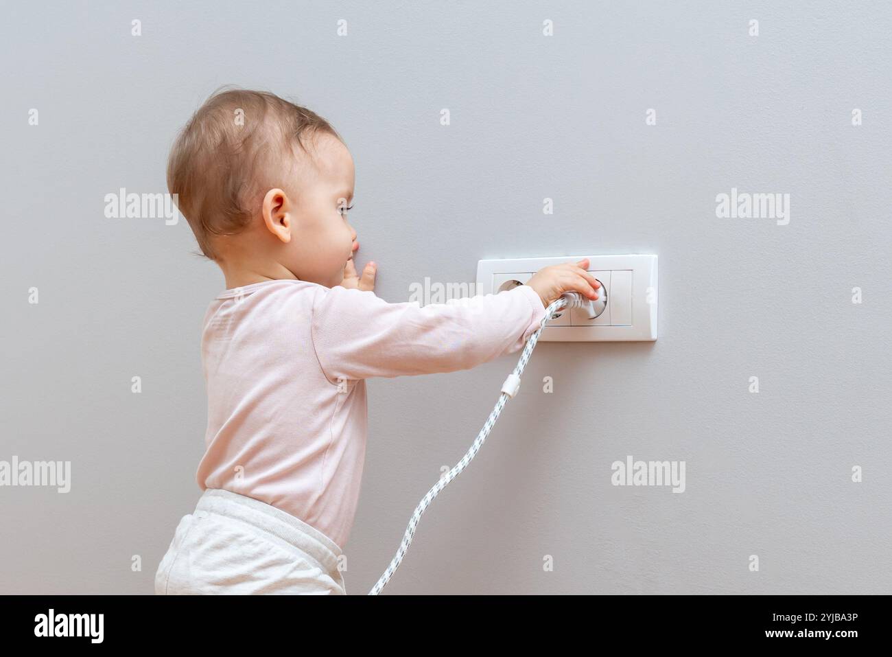 A curious baby explores a plug and outlet, highlighting the importance ... A curious baby explores a plug and outlet, highlighting the importance ...